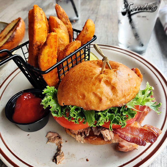 This isn't just a sandwich; it's architecture with bacon. The potato wedges standing at attention like they know they're in the presence of greatness.