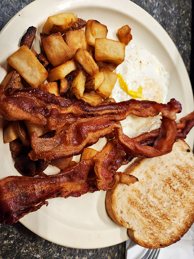 Bacon cooked to that perfect sweet spot between chewy and crisp, alongside golden hash browns that could make a potato farmer weep with pride.