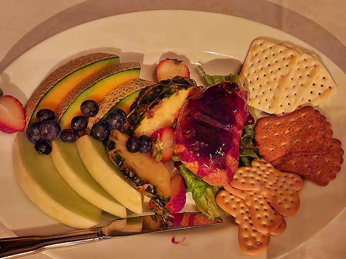 Baked brie transforms into edible elegance with fresh fruit, crackers, and raspberry jewel-toned accompaniment.