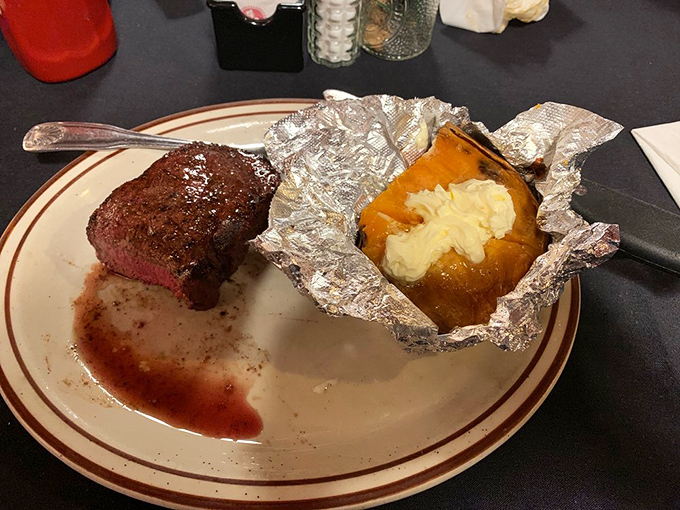 The perfect trifecta: a sizzling steak, buttery baked potato, and garlic bread that would make an Italian grandmother nod in approval.