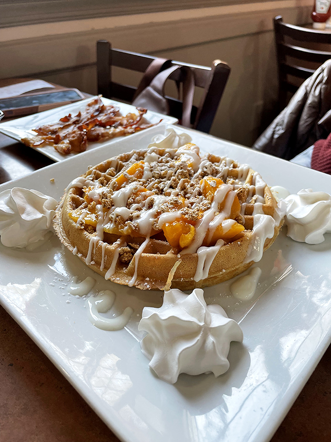 A waffle that's dressed for success with fresh fruit, whipped cream, and what appears to be a sprinkle of "why don't I make breakfast like this at home?"