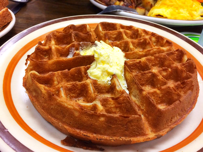 This Belgian waffle isn't trying to win beauty contests—it's too busy being delicious. That butter pool in the center is where breakfast dreams are born.