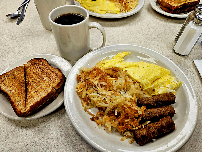 The breakfast trinity: perfectly scrambled eggs, crispy hash browns, and sausage links that snap when you bite them.