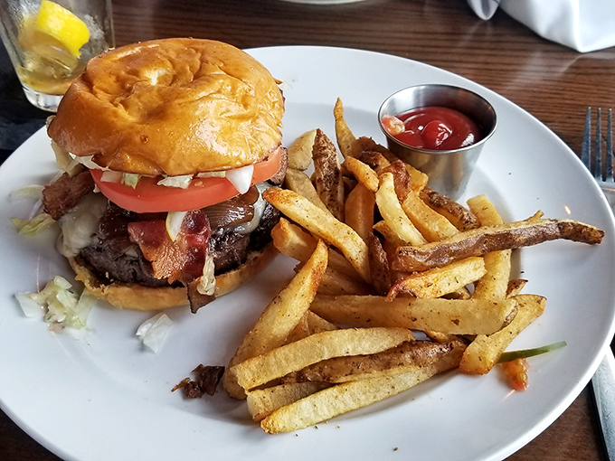 A burger that requires both hands and a strategy. The golden brioche bun somehow containing all that deliciousness is performing architectural miracles.