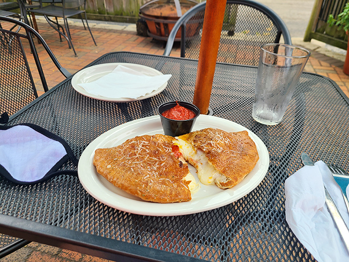 The calzone sits on its outdoor throne, cheese peeking out like it's playing hide-and-seek. One bite and you'll understand why people cross county lines for this.