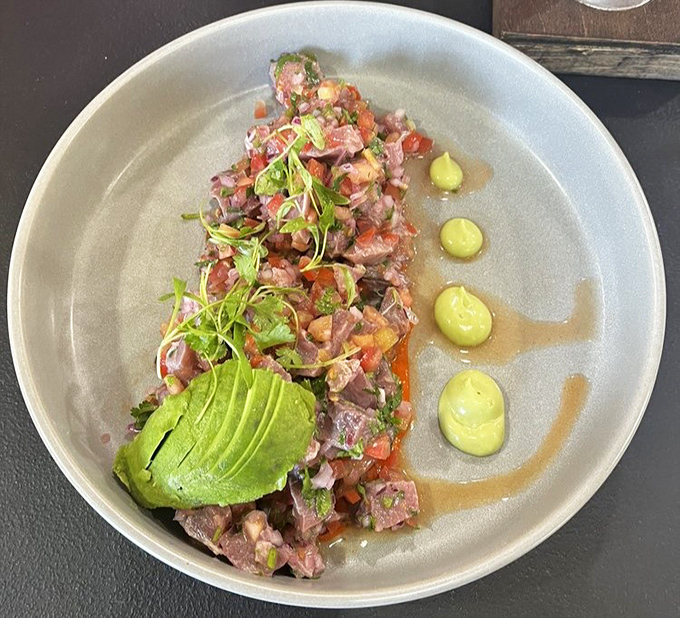 This isn't just ceviche; it's a celebration of raw fish transformed by citrus, with avocado adding creamy contrast and microgreens for a touch of elegance.
