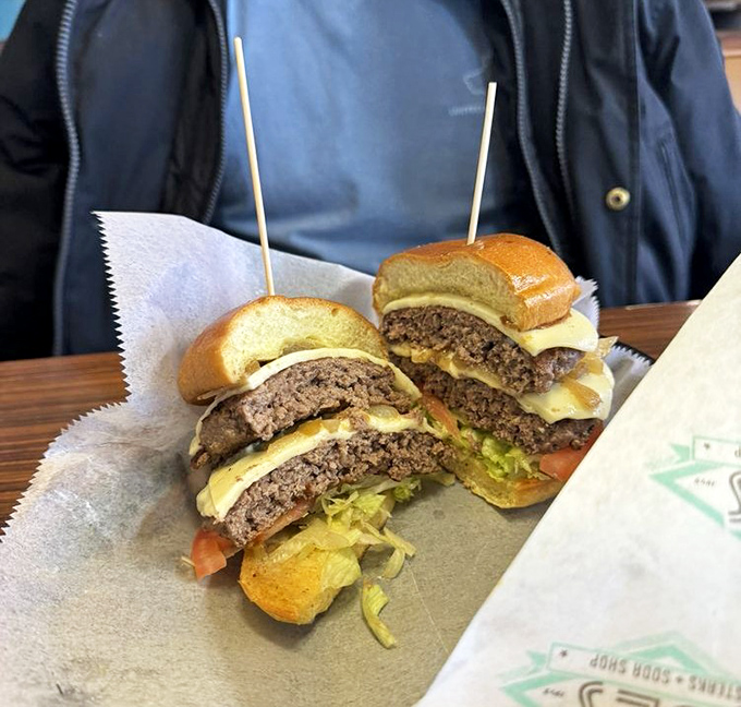 The burger, sliced to reveal its secrets like a delicious archaeological dig revealing layers of beef, cheese, and fresh toppings.