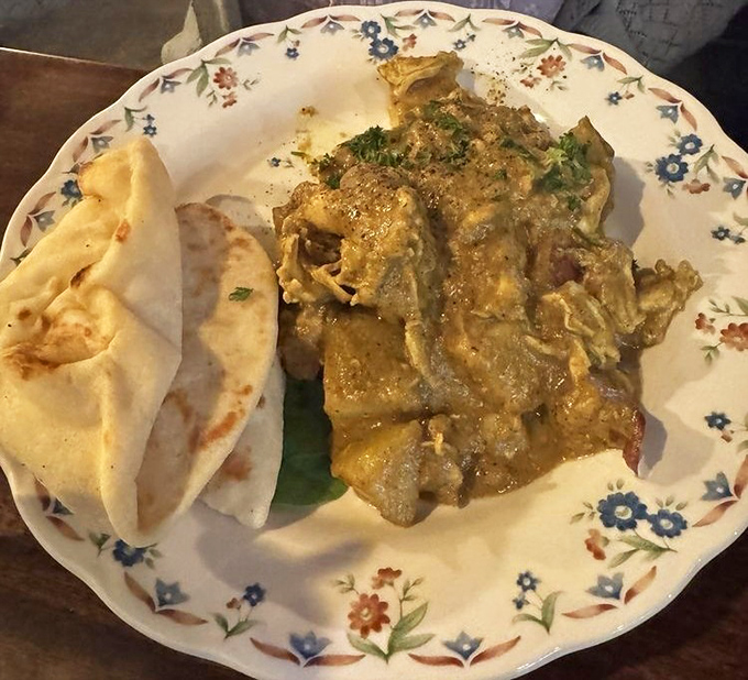 The chicken curry arrives like an ambassador of flavor, accompanied by warm naan bread on a plate that's as pretty as the dish is delicious.