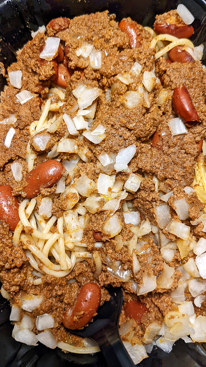 Cincinnati chili in its natural habitat—mingling with spaghetti, beans, and onions. This five-way relationship has lasted longer than most Hollywood marriages.