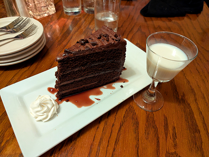 A slice of chocolate cake so rich it should come with its own tax bracket, accompanied by a glass of milk for balance.
