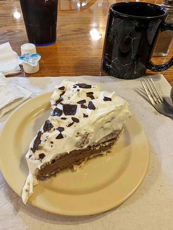 That chocolate cream pie slice stands tall like a sweet skyscraper ready to demolish your diet plans.