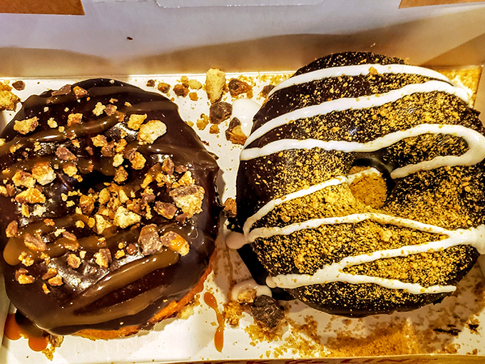 Chocolate donuts with toppings that mean business. The one on the left is having a caramel and nut party that you're definitely invited to.