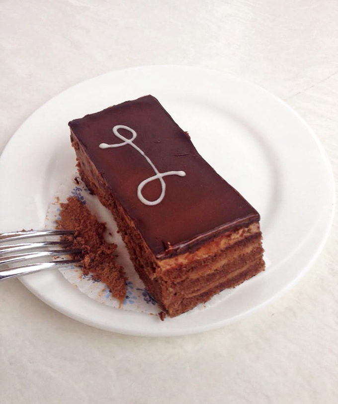 Layers upon layers of chocolate perfection, with that signature "L" saying "Look, you deserve this moment of pure indulgence."