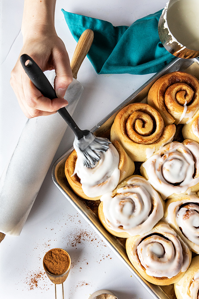 Watching these cinnamon rolls get their finishing touch of icing is like witnessing the final brushstrokes on a masterpiece—except you can eat this art.