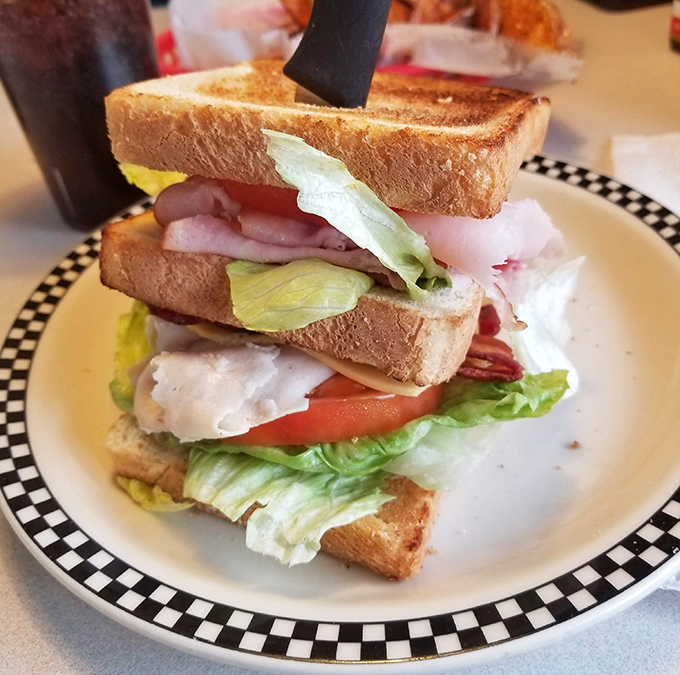 The club sandwich: architectural marvel of the diner world, where each layer tells its own story and cutting it diagonally isn't just style—it's sacred tradition.