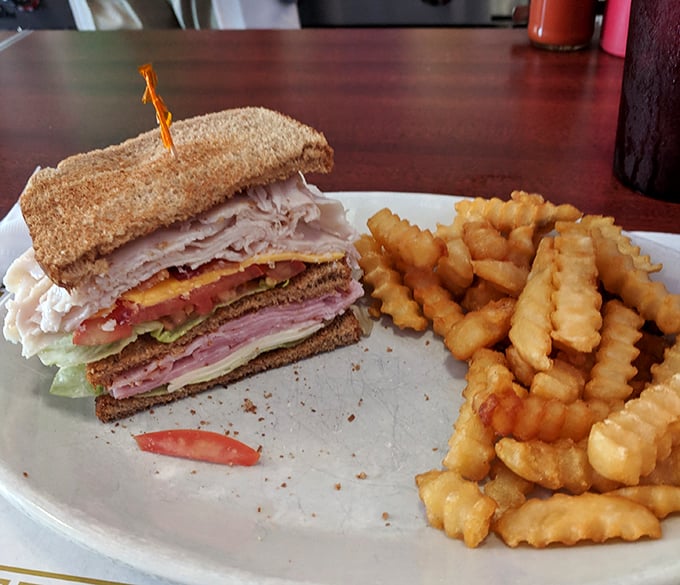 The club sandwich: mankind's greatest achievement in vertical food engineering, accompanied by crinkle-cut fries that demand to be savored.