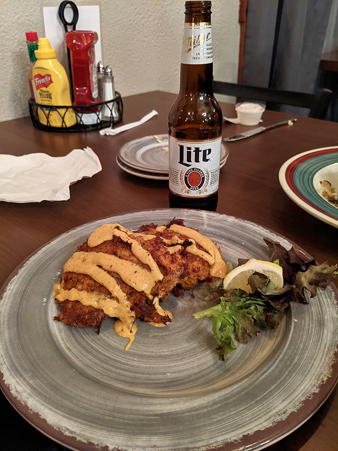 These crab cakes aren't just golden-brown—they're wearing a special sauce beret and posing next to a crisp salad like they know they're the catch of the day.