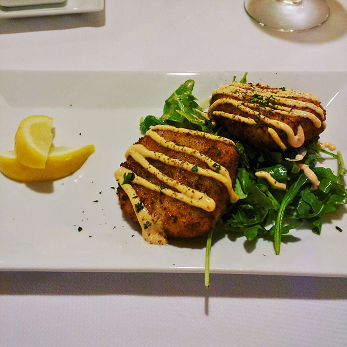 The legendary crab cakes arrive like golden discs of oceanic treasure, with just enough sauce to complement—never overwhelm—the sweet crab meat.