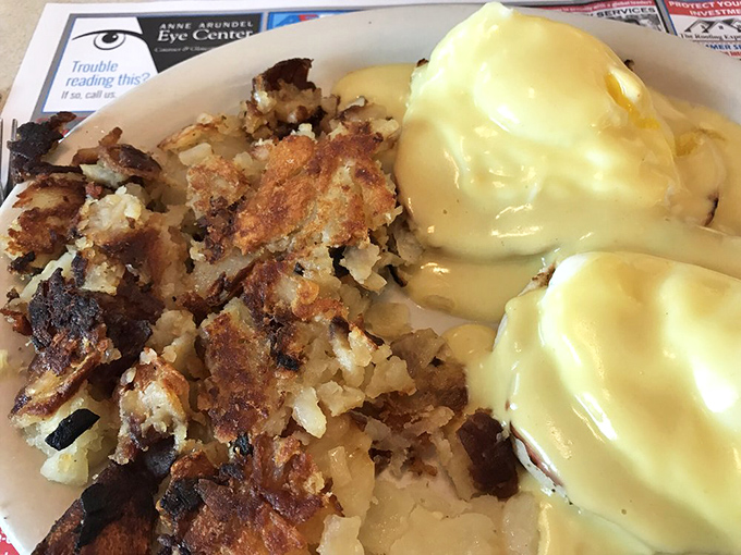 The holy trinity of breakfast indulgence: golden home fries, perfectly poached eggs, and hollandaise sauce that could make cardboard taste delicious.