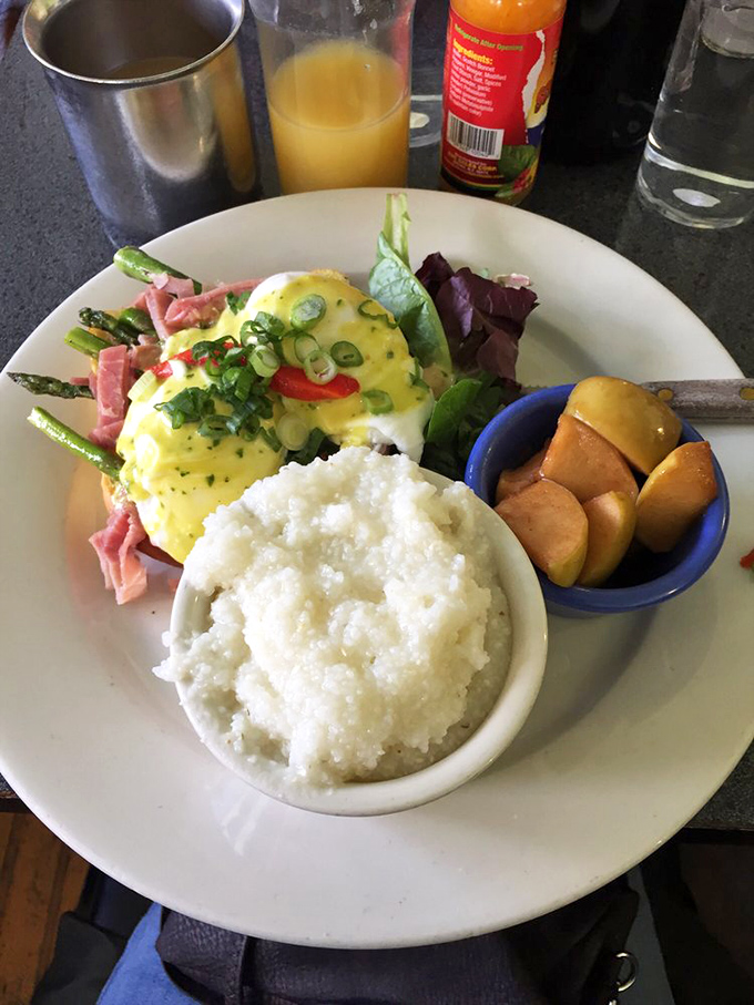 Eggs Benedict reimagined with ham and asparagus—proof that sometimes the classics deserve a thoughtful update and a side of perfect grits.