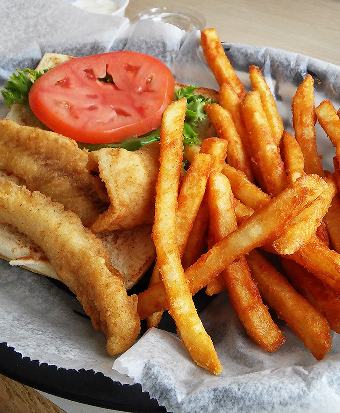 Golden-fried fish with crispy fries and a fresh tomato slice—proof that simple pleasures are often the most satisfying.