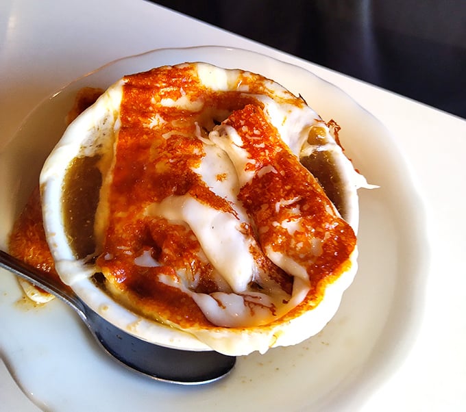 French onion soup: where cheese meets broth in a beautiful, bubbly romance. The spoon stands ready for the perfect first bite.