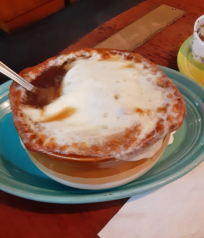 French onion soup with a cheese cap that deserves its own superhero cape. Breaking through that golden dome feels like discovering buried treasure.