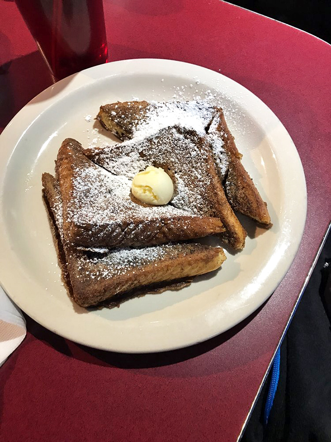 French toast that looks like it graduated from culinary finishing school. Powdered sugar snow falls on golden-brown perfection.