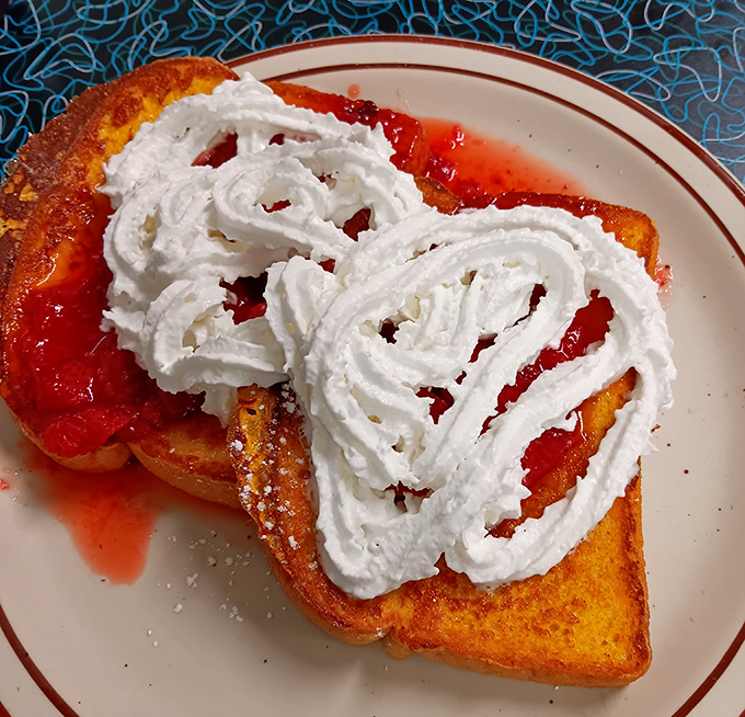 French toast elevated to art form &ndash; crowned with whipped cream and strawberry sauce, it's dessert masquerading as breakfast, and nobody's complaining.