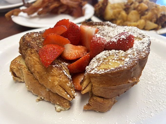 French toast that's crossed the border into dessert territory, crowned with fresh strawberries and a dusting of powdered sugar.