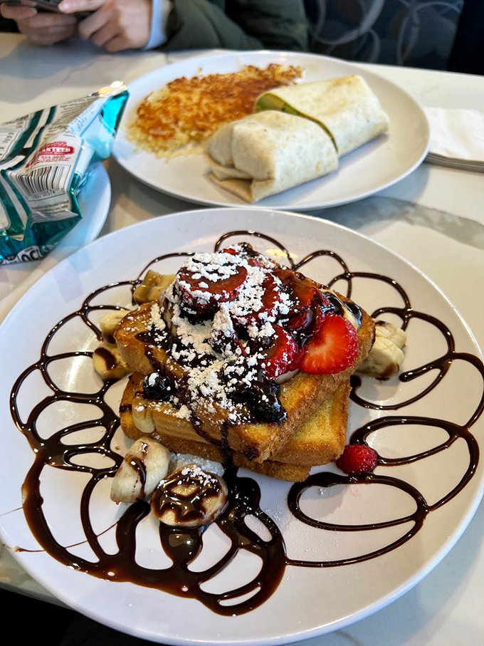 French toast elevated to dessert status with strawberries, bananas, and chocolate drizzle. Breakfast or dessert? The line deliciously blurs.