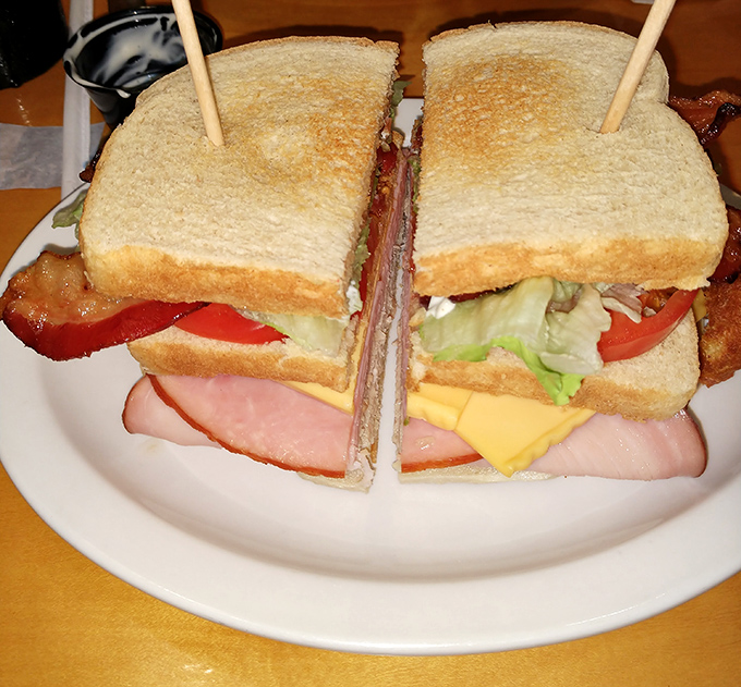 This club sandwich stands taller than most architectural achievements, requiring both strategic planning and an unhinged jaw to conquer.