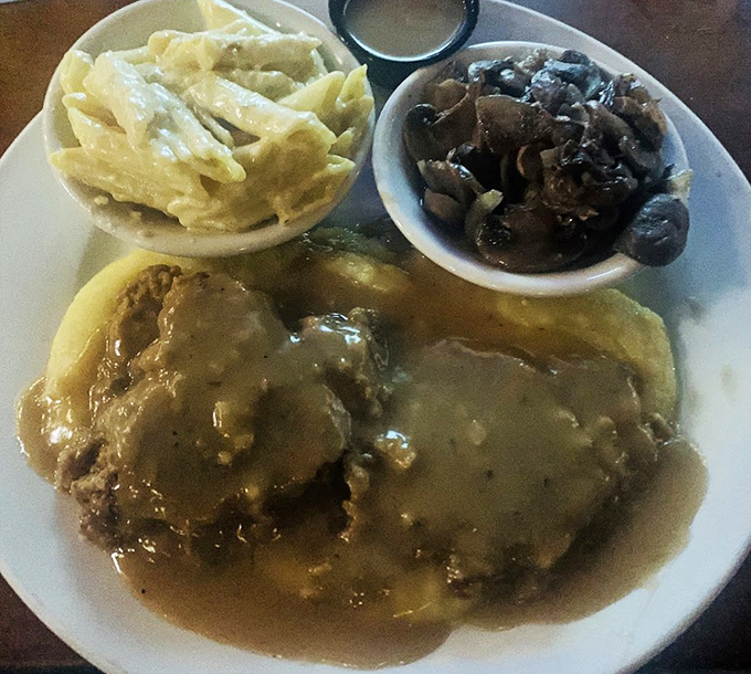 Hamburger steak swimming in savory gravy alongside mac and cheese—the kind of plate that makes you want to hug whoever invented comfort food.