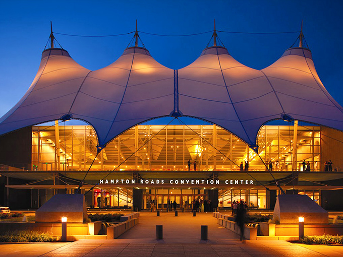 The Hampton Roads Convention Center's illuminated fabric peaks glow like a landlocked regatta, sailing through the evening skyline.
