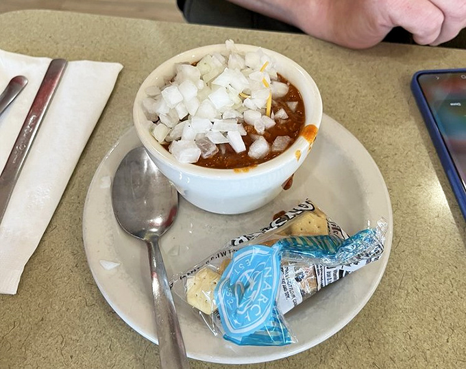 The legendary chili in its natural habitat—crowned with diced onions and crackers standing by, ready for their supporting role.