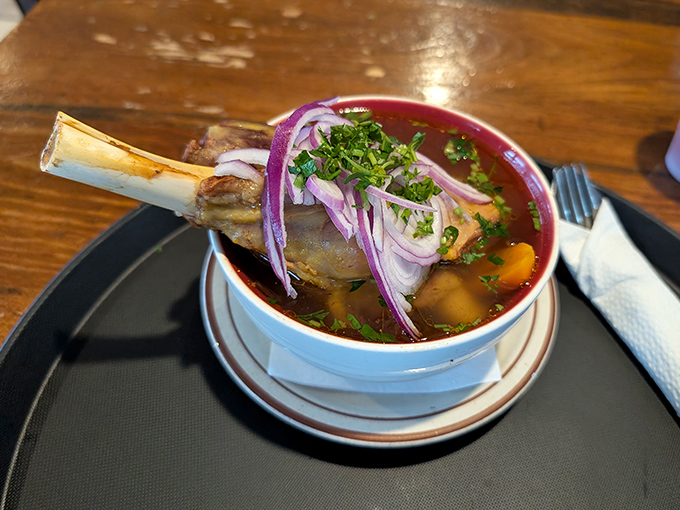 A soup so hearty it comes with its own bone! This lamb shank broth, brightened with fresh herbs and purple onion, is liquid comfort in a bowl.