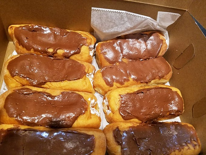 Chocolate-topped long johns lined up like edible dominos, ready to topple your diet plans with their irresistible siren call.