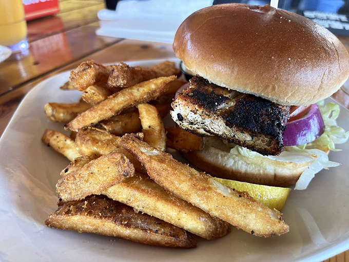 This blackened mahi sandwich isn't just lunch &ndash; it's a monument to what happens when fish meets fire meets skill. Those fries aren't slouching either.