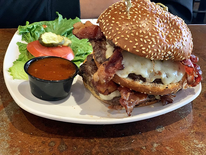 Not all burgers are created equal—this towering creation proves it. The sesame-studded bun barely contains its glorious, bacon-laden contents like a treasure chest overflowing with deliciousness.
