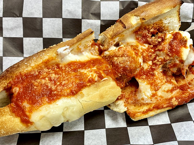 The meatball sandwich, opened to reveal its soul&mdash;tender spheres of seasoned meat bathing in sauce and melted cheese. Poetry on a roll.