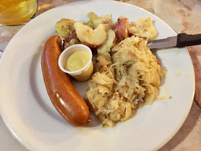 A German sausage lounging on a bed of sauerkraut and potatoes – comfort food that's traveled 4,500 miles to hug your taste buds.