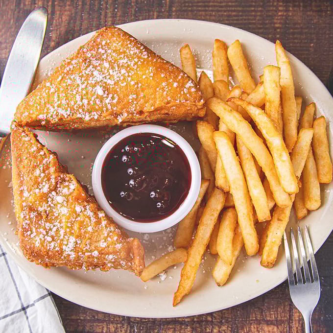 The Monte Cristo: where sandwich meets dessert in a powdered sugar paradise, with raspberry jam standing by for extra indulgence.