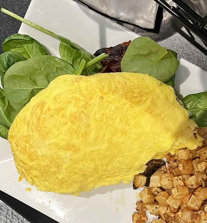 This omelet doesn't just sit on the plate &ndash; it lounges luxuriously, a fluffy yellow pillow of egg perfection alongside crispy breakfast potatoes.