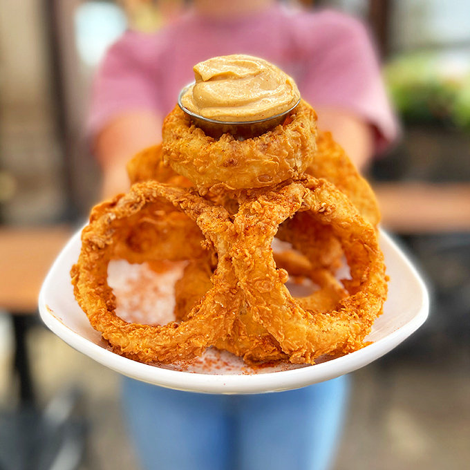Onion rings stacked like edible architecture, each one a crispy circle of deep-fried perfection worth writing home about.