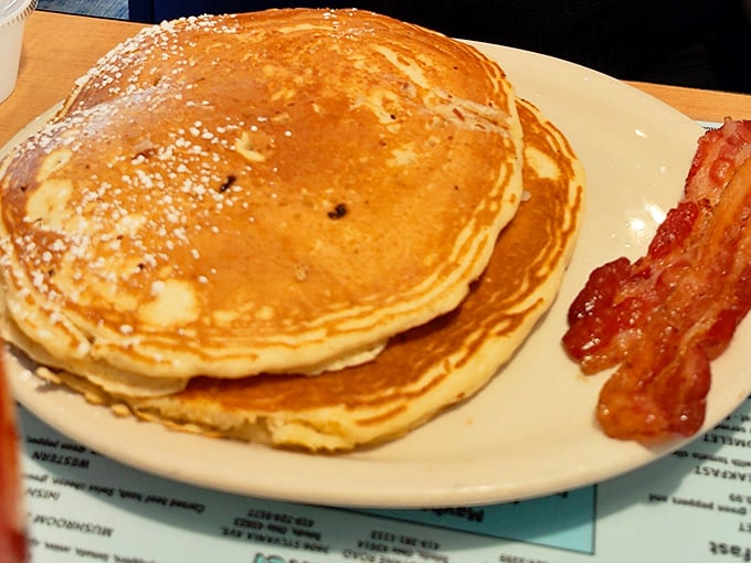 Pancakes so perfectly golden they belong in Fort Knox, with bacon standing guard. The powdered sugar isn't decoration&mdash;it's a blessing from the breakfast gods.