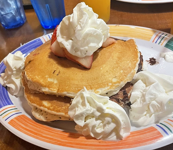 These pancakes aren't just stacked&mdash;they're architectural achievements topped with whipped cream islands and strawberry treasures.