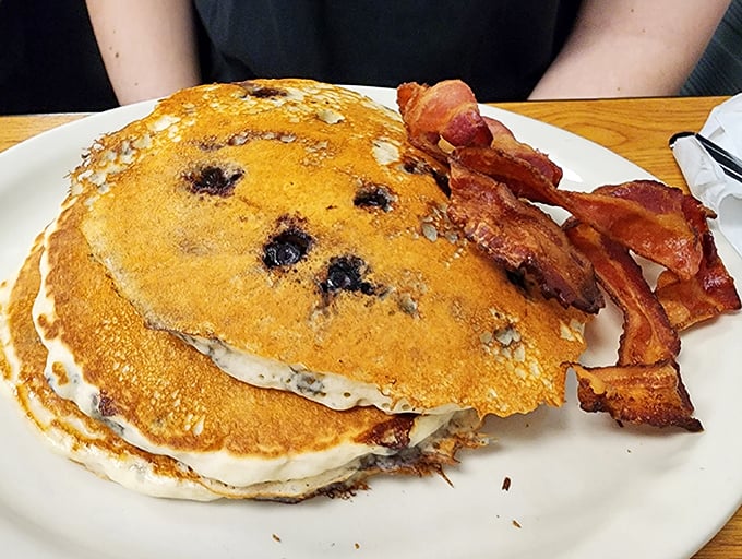 Blueberry pancakes stacked higher than your weekend expectations, with bacon cooked to that magical point between chewy and crisp. Breakfast nirvana exists.