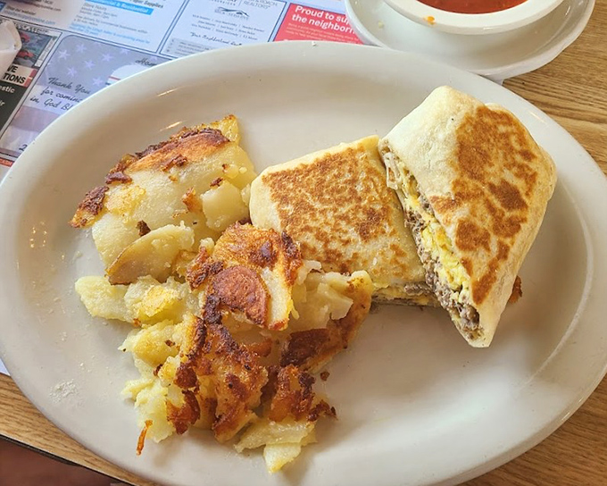 Breakfast sandwich perfection with home fries that look like they've been practicing their crispy-to-tender ratio for decades. This plate doesn't need a filter—it needs a trophy.