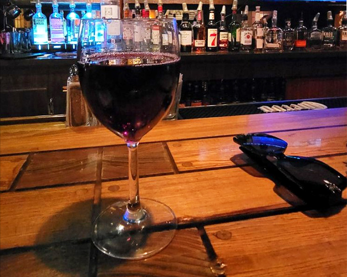 A glass of pinot noir catching the bar light just right&mdash;like liquid ruby waiting to complement whatever beef masterpiece you've ordered. 