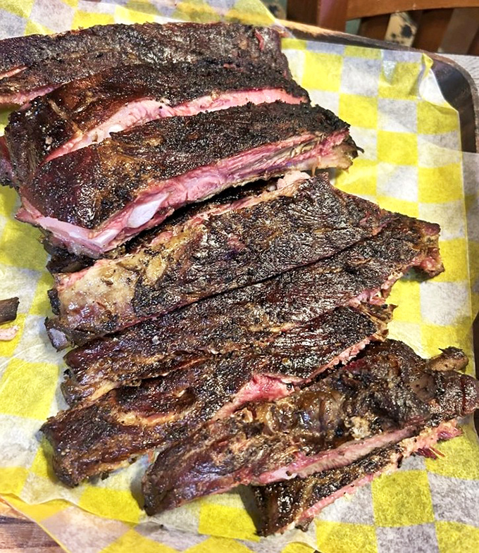 These ribs have the kind of bark and pink smoke ring that make barbecue judges weep with joy. The yellow checkered paper is just trying to contain the glory.